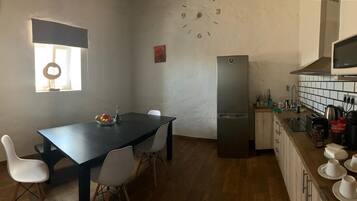 Uma cozinha compacta com geladeira, micro-ondas e um pequeno espaço de refeições com mesa e cadeiras.