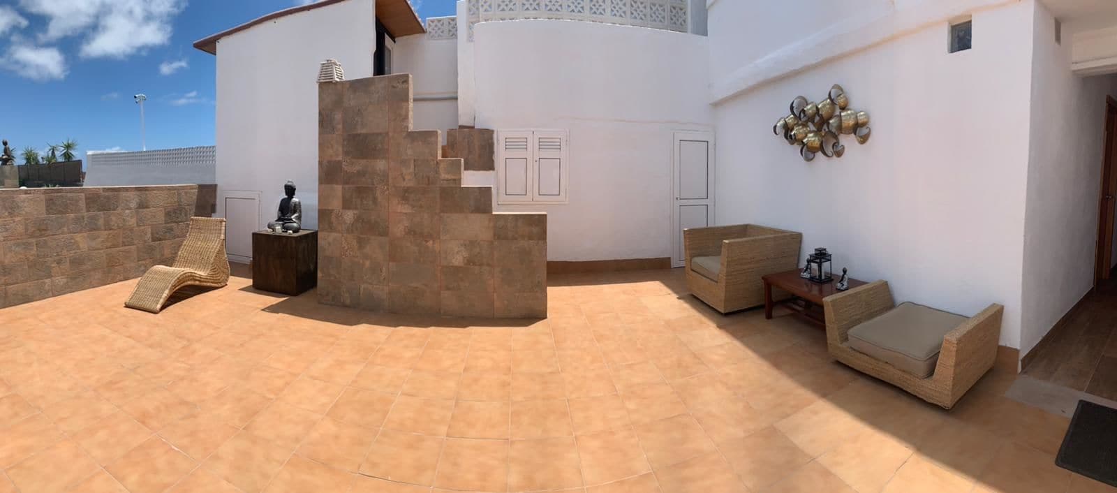 Um pátio espaçoso com escadaria de pedra, móveis de vime e um muro decorativo.