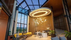 Um lobby moderno com uma recepção em curva, área de estar e grandes janelas com vista para o exterior.