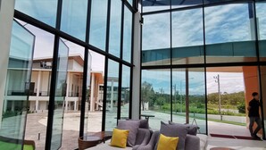 Um interior moderno com uma grande parede de vidro, um conjunto de sofás e uma mesa de madeira exclusiva.