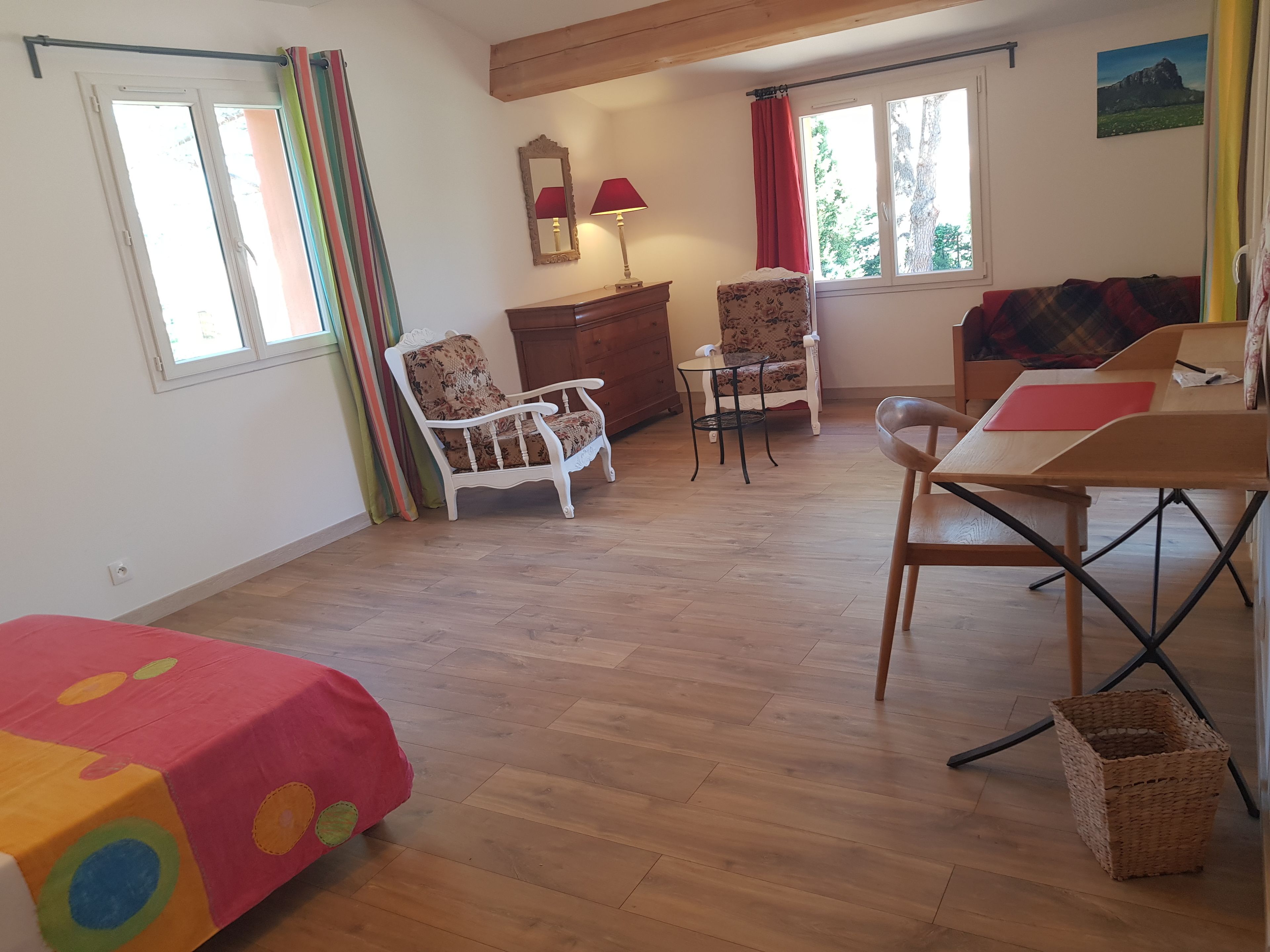 Um quarto com cama, escrivaninha, cadeira, mesa e sofá.