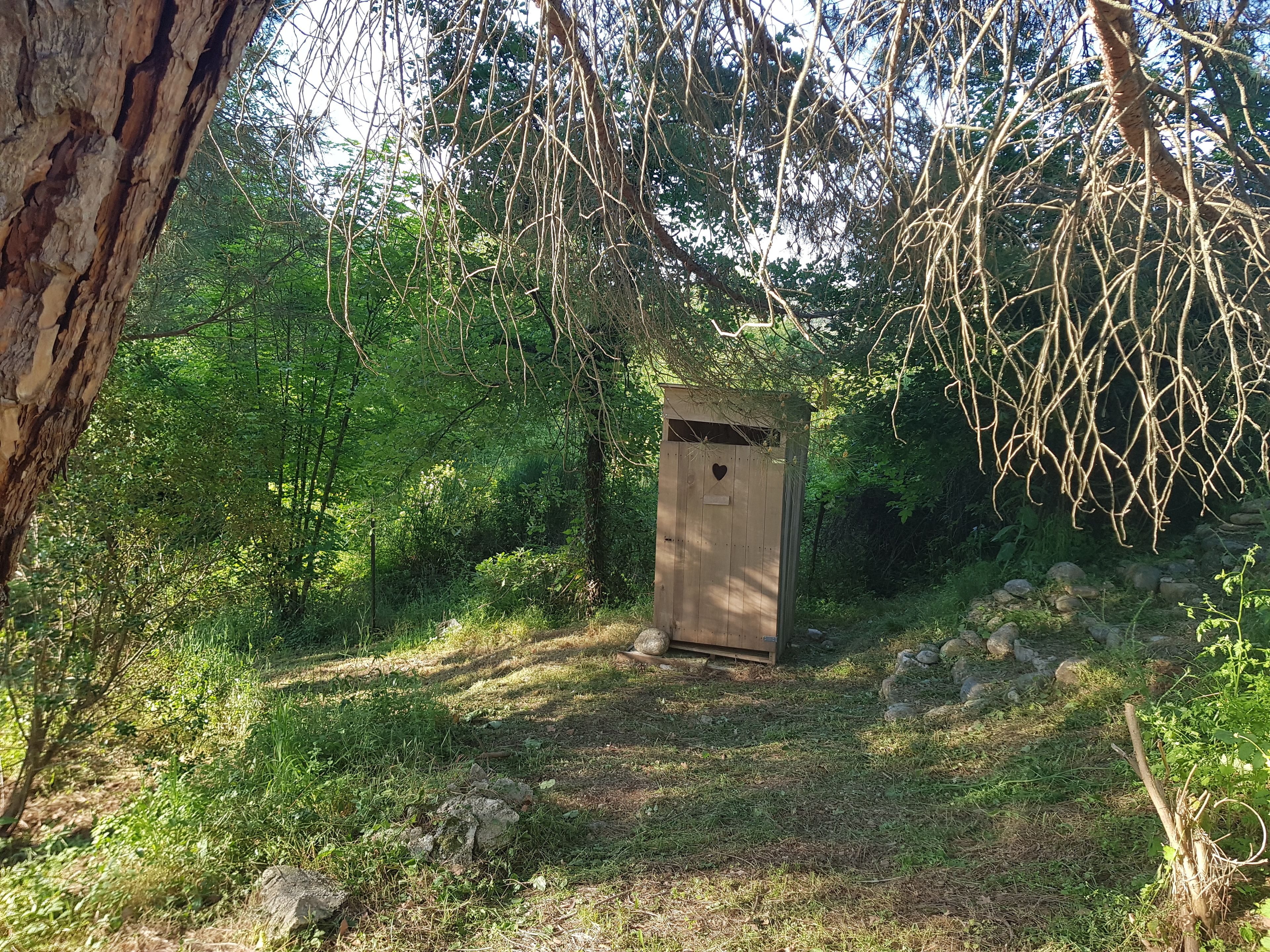 Pequena estrutura de madeira numa área arborizada, com um caminho que a leva até ela.