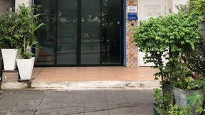 Edifício com uma grande entrada de vidro, toldo azul e o número 1668. Há plantas em vasos na frente.