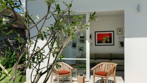 Uma área externa moderna com parede de vidro, um banco de madeira e um sofá.