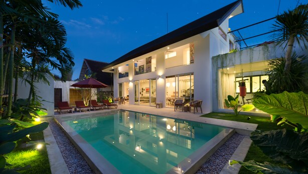Uma casa moderna com piscina, área de estar externa e vegetação exuberante.