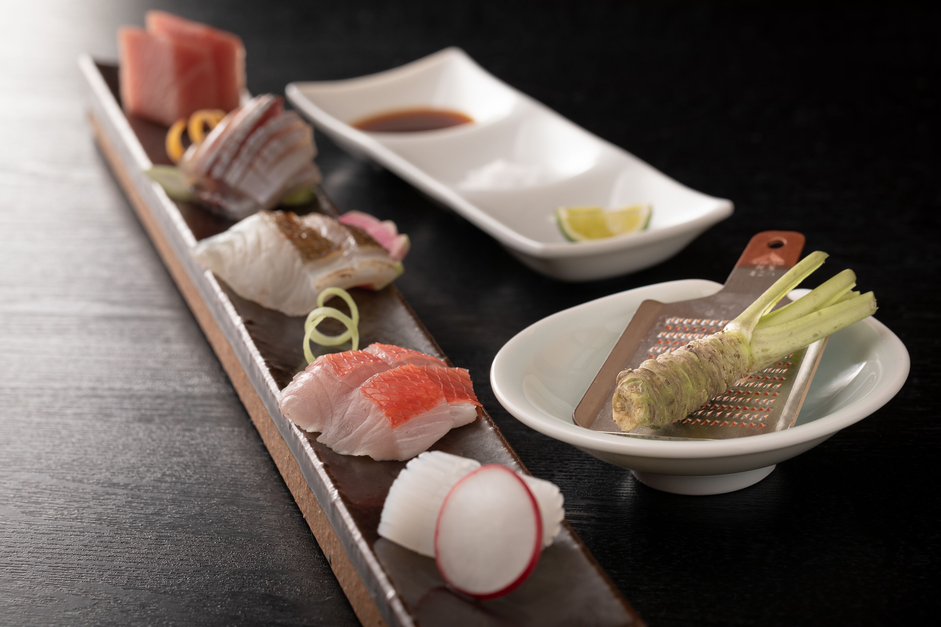 Uma seleção de sushi com diversos tipos, acompanhada de um recipiente com wasabi e gengibre.