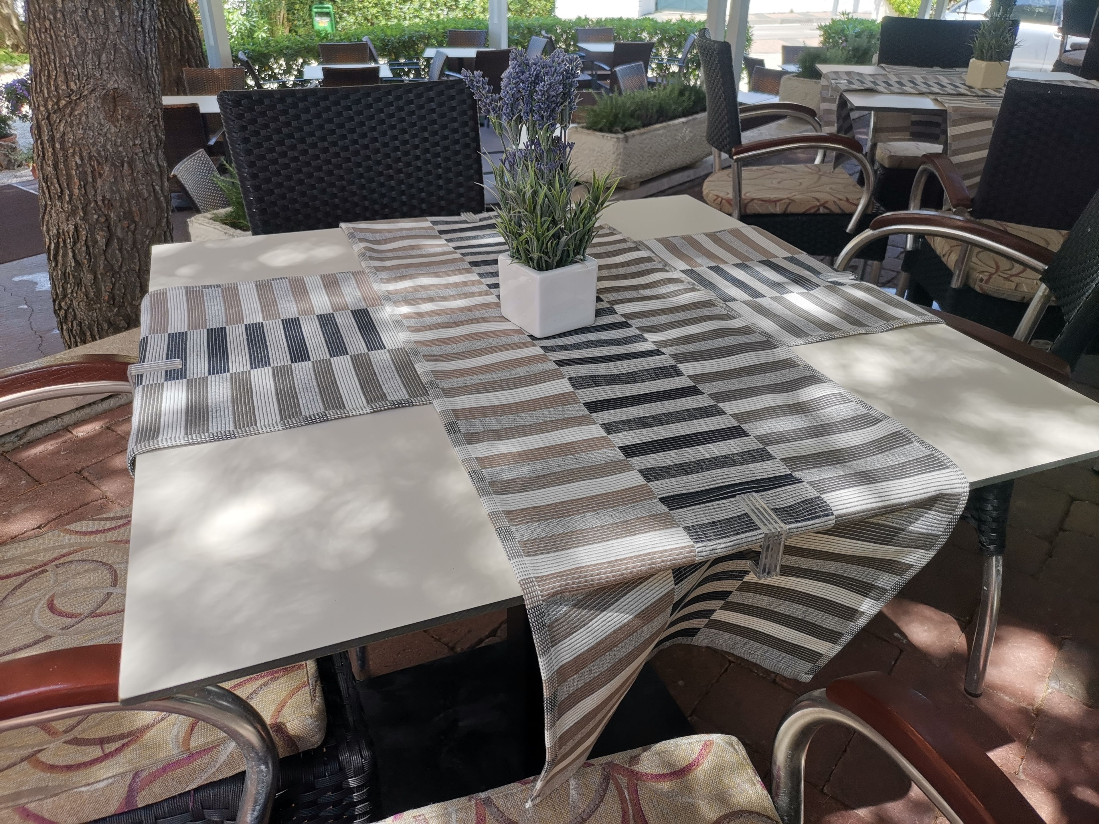 Uma mesa com toalha listrada, rodeada por cadeiras com assentos e encostos acolchoados.
