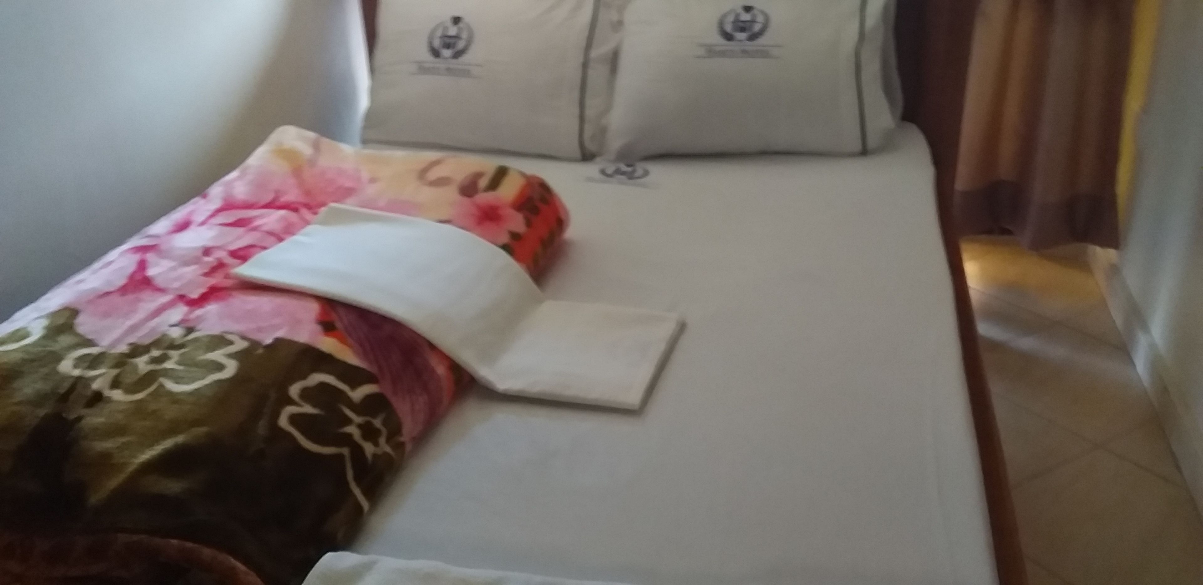 Uma cama com colcha florida e duas almofadas com um logotipo.