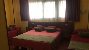 Quarto de hotel com uma cama grande, duas mesas de cabeceira e uma janela com cortinas.