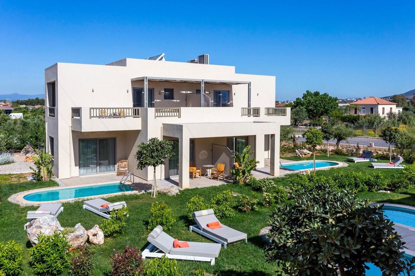 Uma casa moderna de dois andares, com piscina, área de estar externa e um jardim bem cuidado.