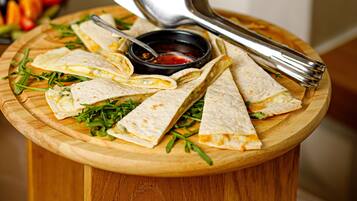 Uma mesa de madeira com um prato de quesadillas e uma tigela de molho.