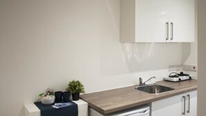 Cozinha moderna com armários brancos, bancada de madeira, máquina de lavar louça embutida e uma pia pequena.