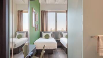 Quarto de hotel com duas camas, uma escrivaninha e uma cadeira. As janelas têm cortinas e as paredes são verdes.