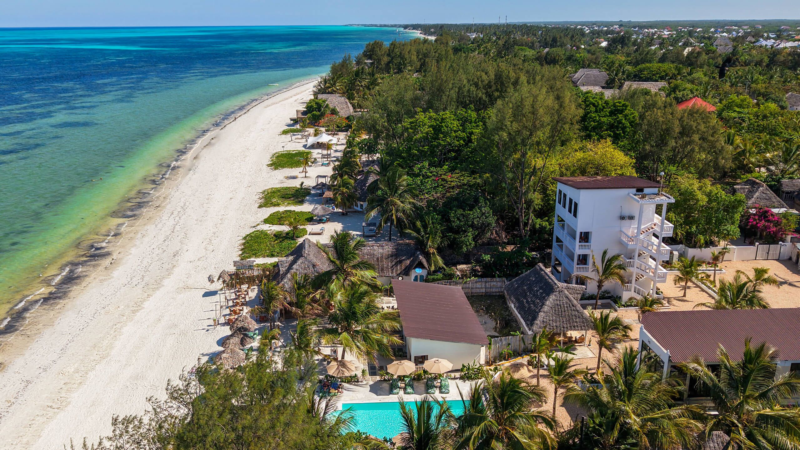 Resort costeiro com praia, piscina e vários edifícios.