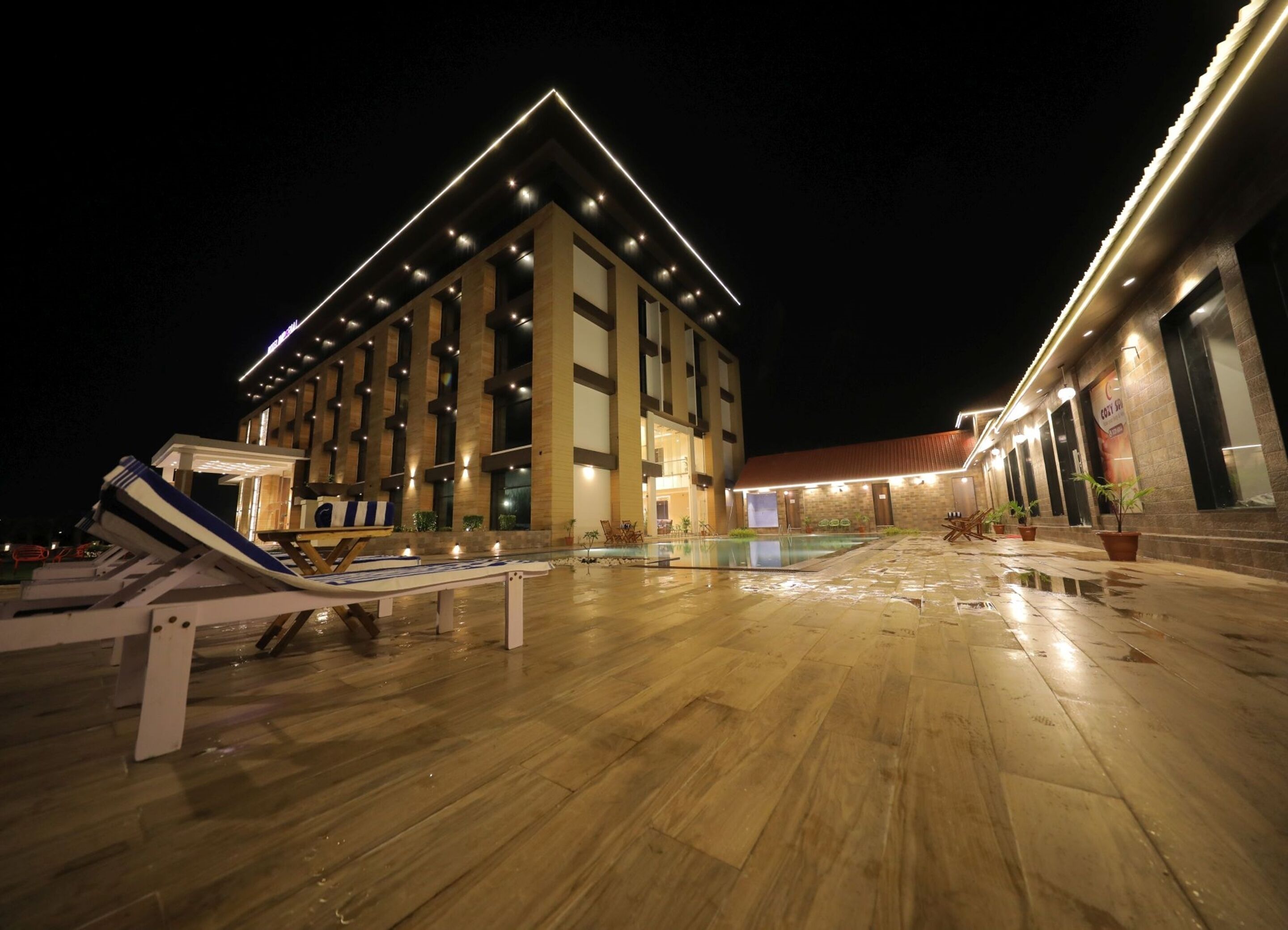 Um hotel com área de piscina, vários andares e fachada bem iluminada.