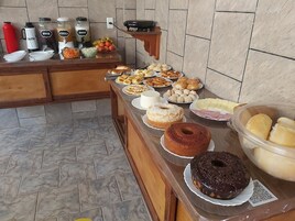 Um balcão de buffet com diversos alimentos, incluindo doces, frutas e bebidas.