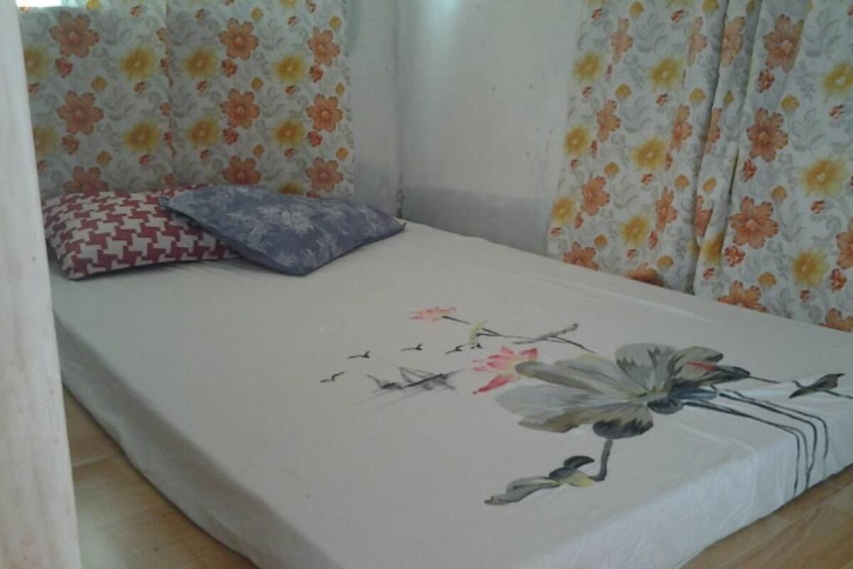 Uma cama com colcha florida, almofada estampada e cortinas com padrão floral.