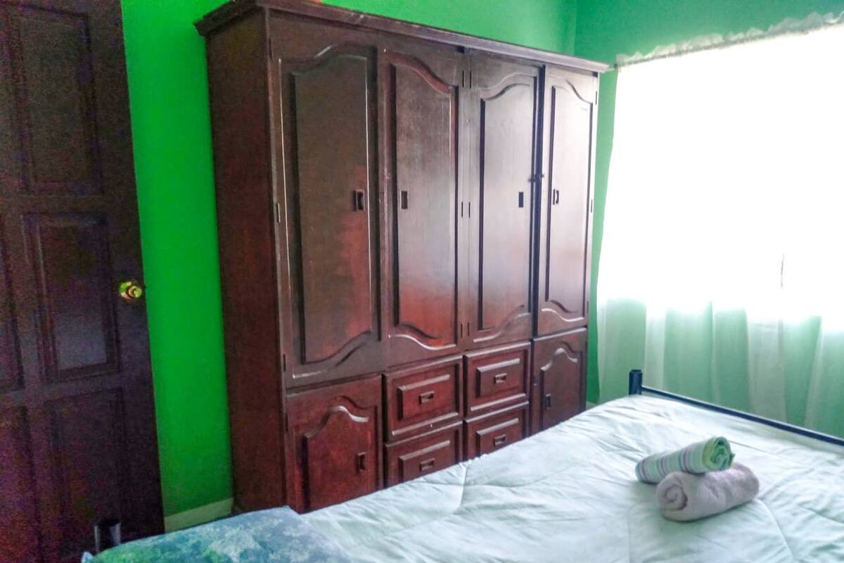 Quarto com uma cama, um guarda-roupa e uma parede verde.