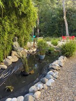 Um jardim tranquilo com uma estátua de Buda, um pequeno lago e uma cerca de madeira.