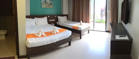 Quarto de hotel com duas camas, uma escrivaninha, uma cadeira e uma janela grande.