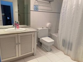 Casa de banho com lavatório branco, sanita e cortina de chuveiro.