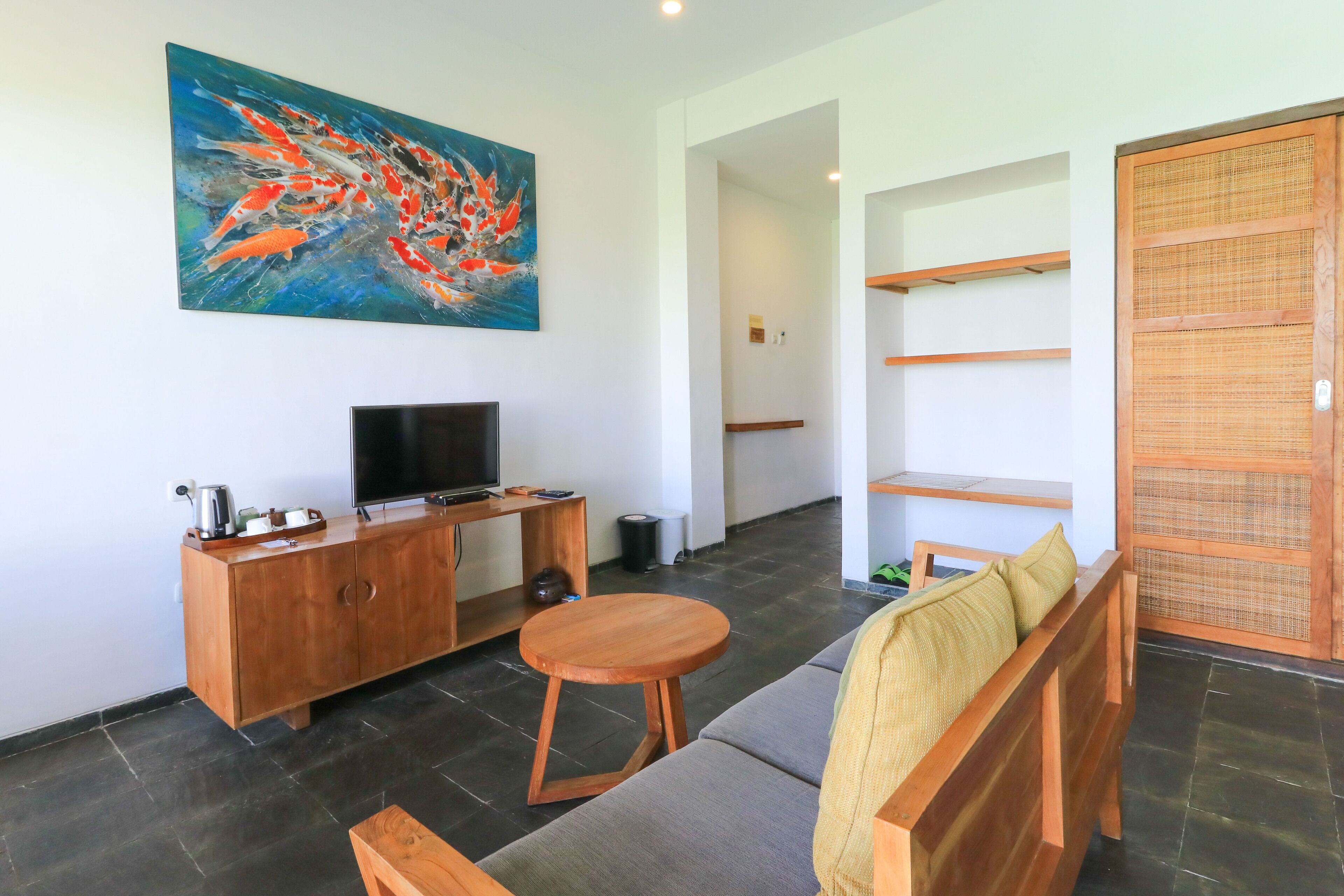 Uma sala de estar moderna com um sofá, uma mesa de centro de madeira, uma TV em um armário de madeira e um quadro de carpas.