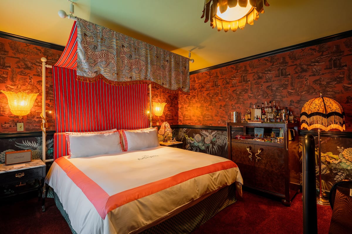 Quarto tradicional com cama, mesa de cabeceira, cômoda e abajur.