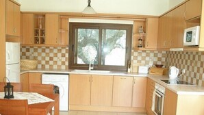 Uma cozinha compacta com armários de madeira, uma janela, pia, micro-ondas e um espaço de refeições com mesa e cadeiras.