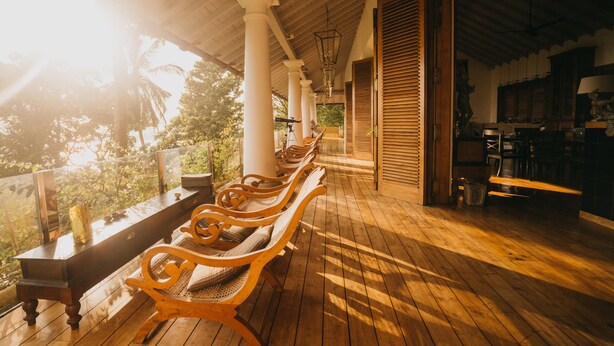 Um deck de madeira com bancos e uma mesa, com vista para um jardim exuberante.