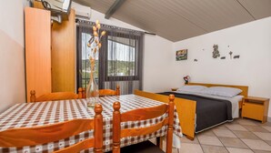 Quarto com cama, mesa de cabeceira e janela com cortinas.