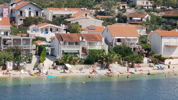 Uma área residencial à beira-mar, com casas, praia e mar azul cristalino.