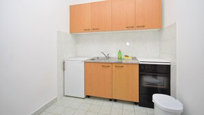 Uma cozinha compacta com armários de madeira, geladeira branca, pia, fogão e vaso sanitário.