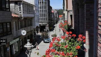 Uma rua estreita com edifícios de ambos os lados, uma área para pedestres e flores vermelhas em vasos.