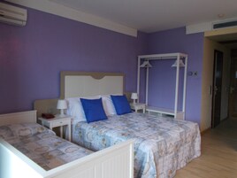 Quarto com duas camas, mesa de cabeceira e guarda-roupa.