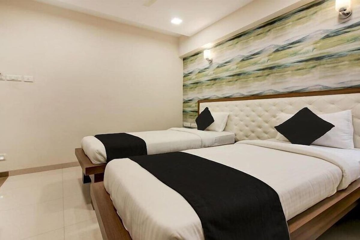 Quarto de hotel com duas camas, um quadro abstrato grande na parede e design moderno.