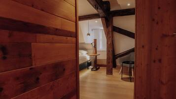 Um quarto com painéis de madeira, teto inclinado, uma cama e uma cadeira.