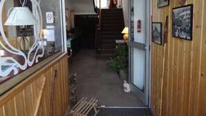 Um corredor estreito com paredes de madeira, uma porta de vidro e uma escada que leva a um andar superior.