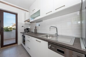Uma cozinha moderna com armários brancos, uma pia de aço inoxidável e uma máquina de lavar louça.