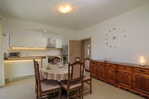 Cozinha moderna com armários brancos, uma mesa de jantar com cadeiras e um aparador de madeira com gavetas.