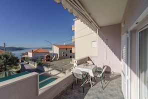 Varanda com mesa e cadeiras, com vista para uma área residencial com casas e céu limpo.