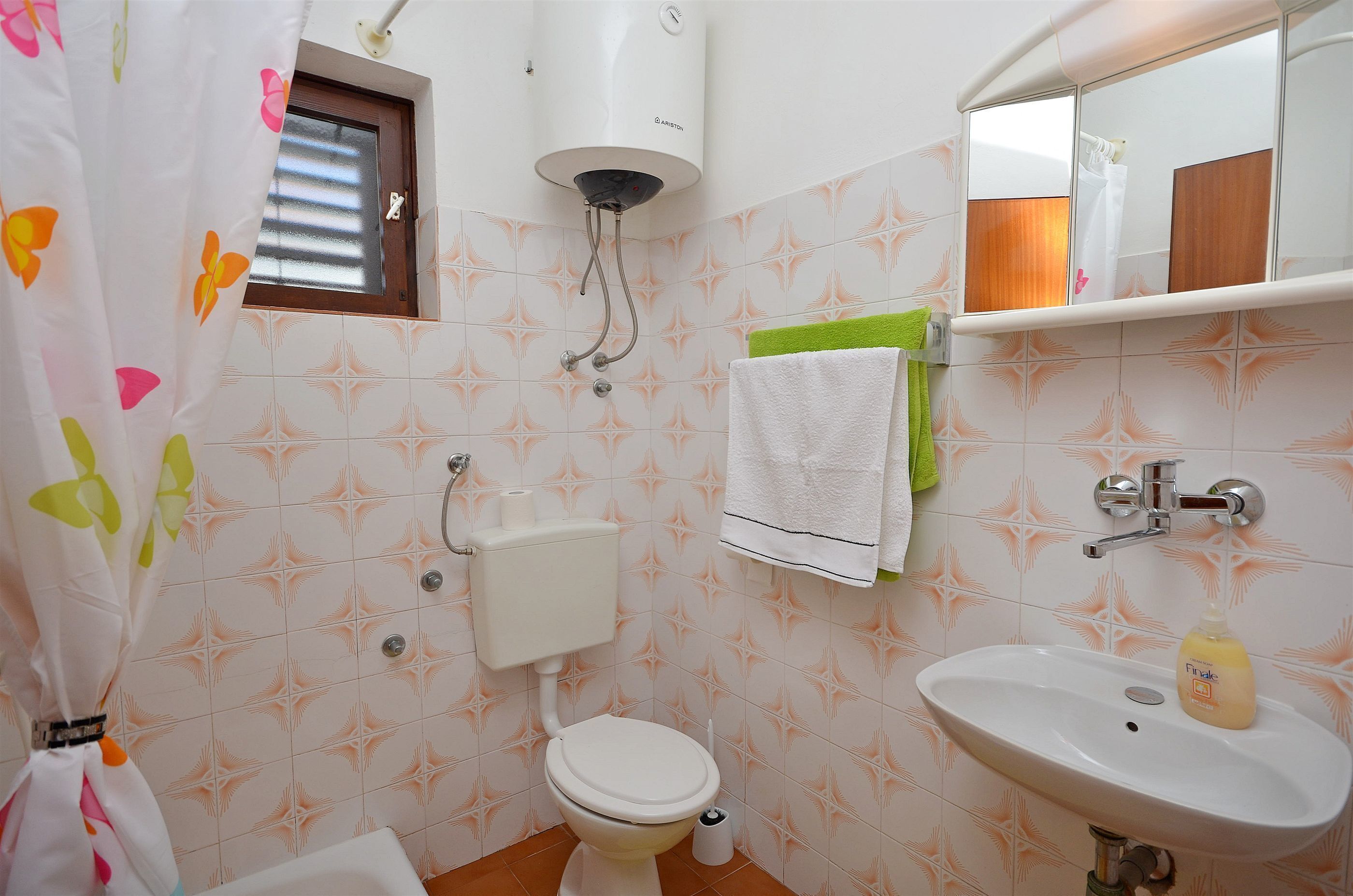 Casa de banho com sanita, lavatório e chuveiro.