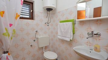 Casa de banho com sanita, lavatório e chuveiro.