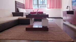 Uma sala de estar moderna com um sofá seccional, uma mesa de centro e uma TV sobre um móvel.