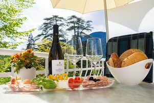 Mesa posta com garrafa de vinho, copos, um cesto de pão e um tábua de frios com diversos carnes e vegetais.