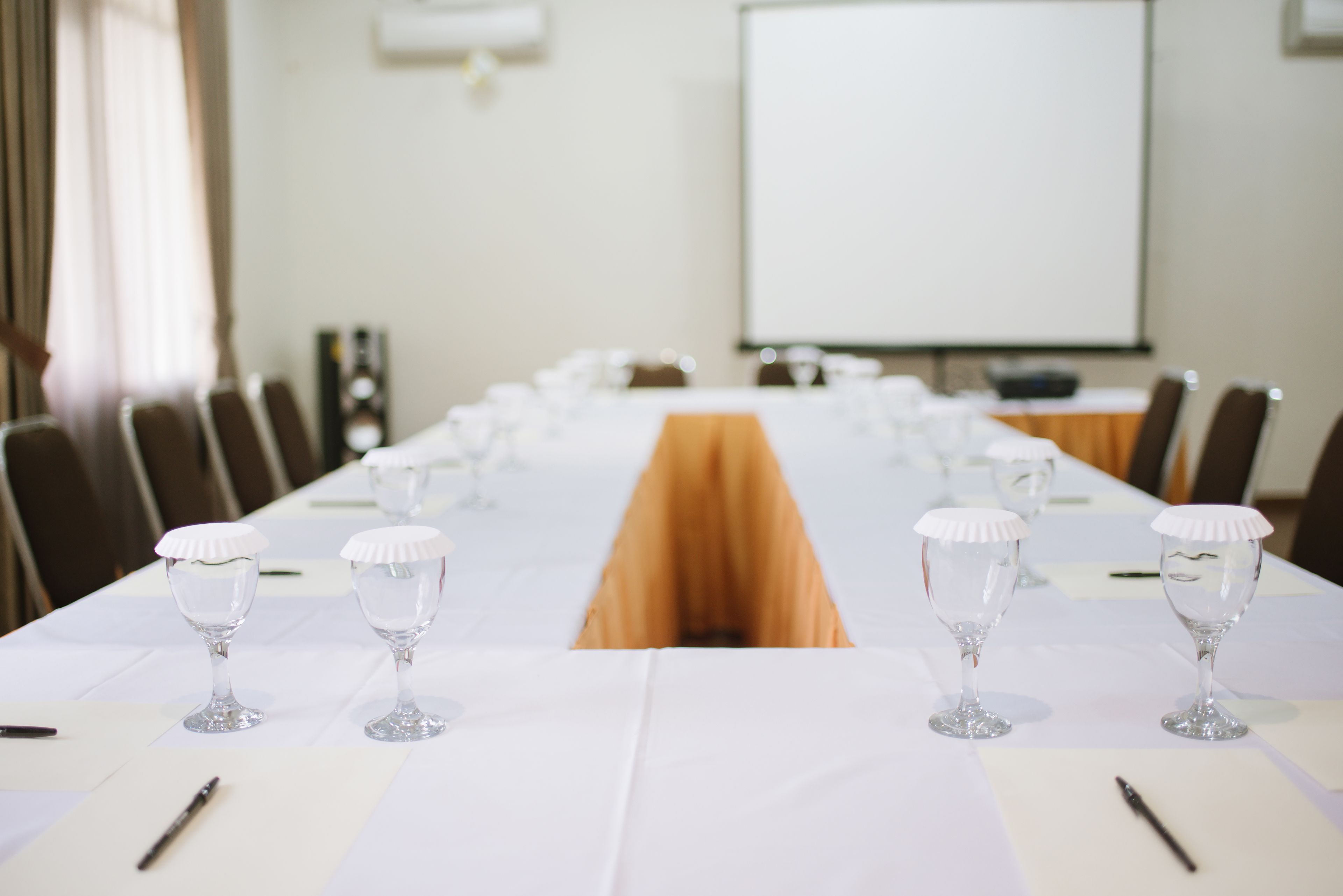 Uma sala de conferências com uma mesa comprida, cadeiras e copos de vinho.