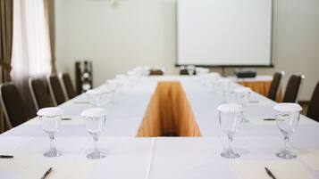 Uma sala de conferências com uma mesa comprida, cadeiras e copos de vinho.