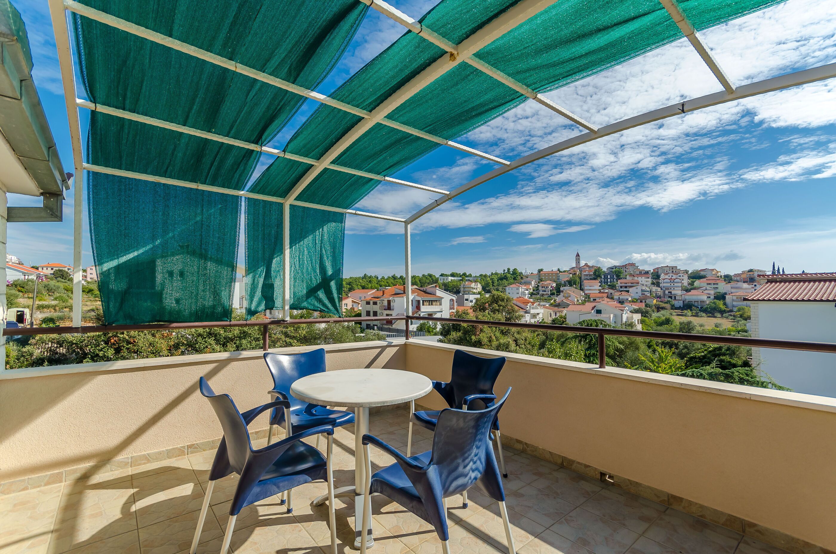 Varanda com mesa e cadeiras, vista para uma cidade e cobertura verde.