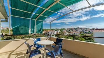 Varanda com mesa e cadeiras, vista para uma cidade e cobertura verde.