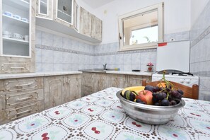 Uma cozinha com armários de mármore, fogão a gás e uma fruteira sobre a mesa.