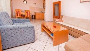 Uma sala de estar com sofá, mesa de centro e um espaço de jantar com cadeiras e mesa.